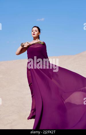 Young Indian female in a purple traditional dress using a smartphone ...