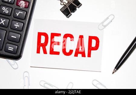 RECAP word on white card paper sheet on blue table with white planner ...