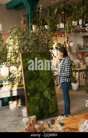 Lady gluing green plant on round mirror Stock Photo - Alamy