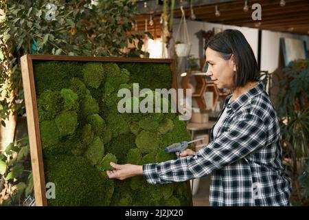 Creative lady gluing green plant on picture Stock Photo - Alamy
