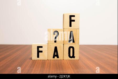 FAQ word on wooden block on top of laptop with blurred nature ...
