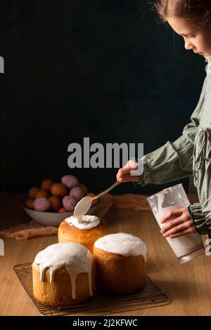 A girl smears Easter cakes with icing, photo in a rustic style Stock ...