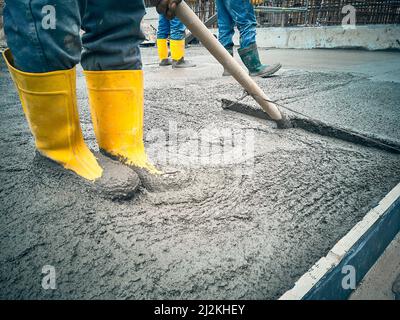 Worker spreading and flattening cement mortar with hand tool, making ...