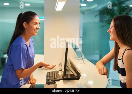 Healthcare Worker Assisting Patient at Reception Desk with Forms in ...