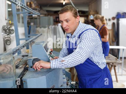 Male glazier working on glass chamfering machine Stock Photo - Alamy