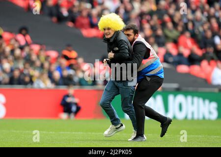 A steward apprehends the Sutton United fan on the pitch Stock Photo - Alamy