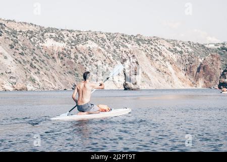 Side view foto of a man swiming and relaxing on the sup board. Sportive ...