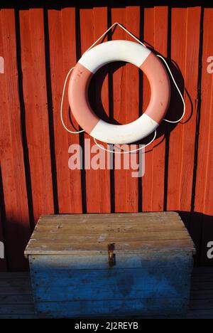 A red and white lifebuoy hanging on the side of a wooden booth at a ...