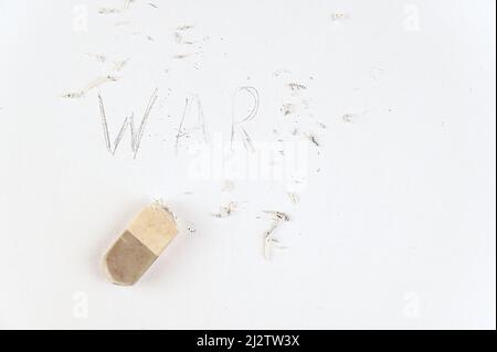Half-erased with an eraser is the word WAR. Handwritten word on white ...