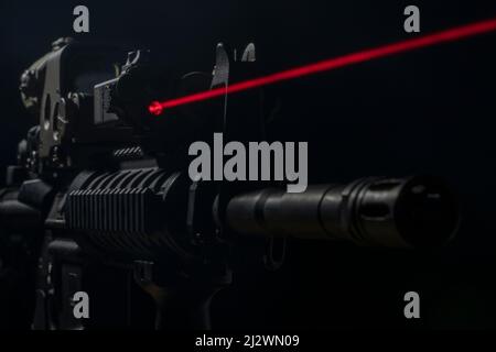 Optical sight and laser device with a red beam on the M4 rifle on dark ...