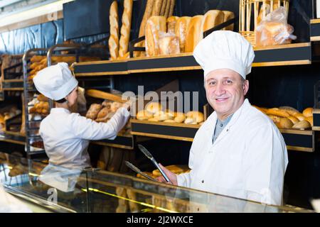 Portrait of satisfied bakers with fresh bread smiling in bakery Stock ...