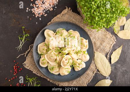 Dumplings with pepper, salt, herbs, microgreen on gray concrete ...