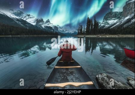 Beautiful aurora borealis over spirit island with female traveler on ...
