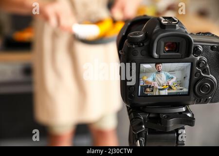 Male chef with fried vegetables recording video in kitchen Stock Photo ...