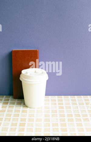 Notebook, holder with stationery, cup of coffee and pine cones on ...