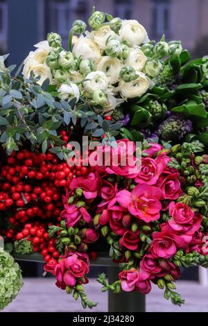 Spring bouquet of white ranunculus and red tulips in a glass round vase ...