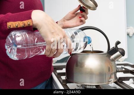 woman pouring clean water from a bottle into a kettle. High quality ...