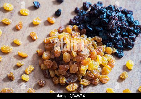 Two small bunches of raisins on a brown table, one of light grapes and ...