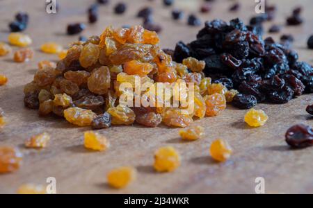 Two small bunches of raisins on a brown table, one of light grapes and ...