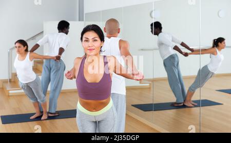 Athletic korean woman performing paired yoga exercises with male ...