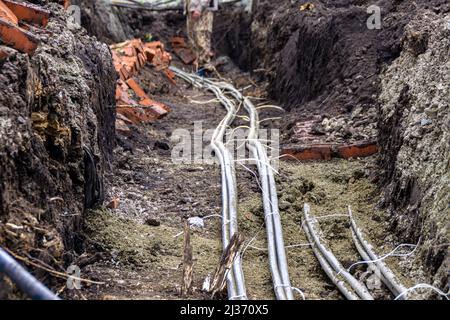 Excavation of trench with black cables in protective HDPE tube. Lines ...