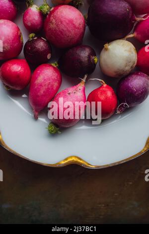 trimmed pink, red, purple, white radishes on white plate with gold ...