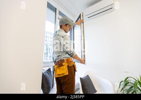 master changing a double-glazed window in a plastic window, side view ...