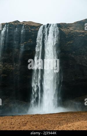 Natural waterfall coming out of a cliff full of trees Stock Photo - Alamy