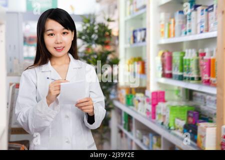 Chinese woman pharmacist keeps track of drugs in interior of pharmacy ...