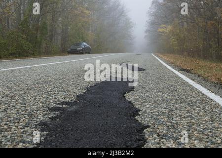 Fresh patches after patching the road. Country highway in the foggy ...