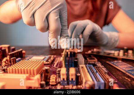 Repair engineer holds RAM chip with hands and inserts RAM of computer ...
