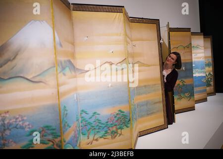 Curator Rachel Peat adjusting one of a pair of screen paintings (byobu ...
