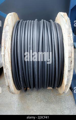 New black power cable is wound on wooden coil. Background. Cable for ...