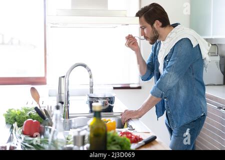 The steam from A man hand lifting a glass lid of the pot in the kitchen ...