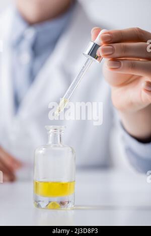 cropped view of laboratory assistant holding aloe and container with ...