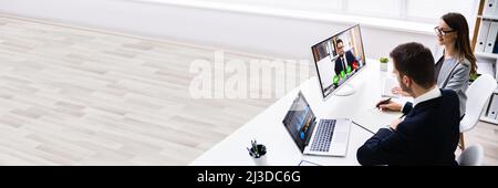 Two Young Businesspeople Video Conferencing On Computer At Office Stock ...