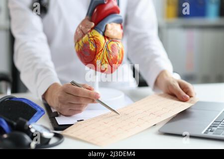 Doctor cardiologist examines electrocardiogram of patient heart in ...