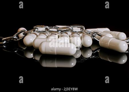 Drug addiction. White capsules rewound by a chain Stock Photo - Alamy