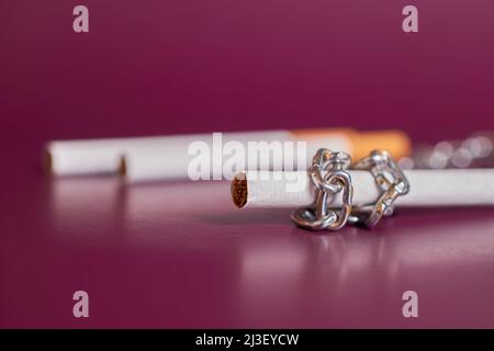 Nicotine addiction. Three cigarettes rewound by a chain Stock Photo - Alamy