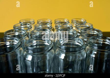 Frontal shot of empty glass jars lined up in a row on a gyellow ...