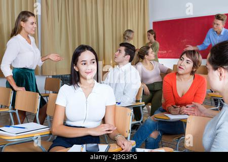 Friendly student group talking in classroom having break between ...