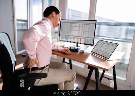 Man with bad posture using tablet while sitting on chair against grey ...