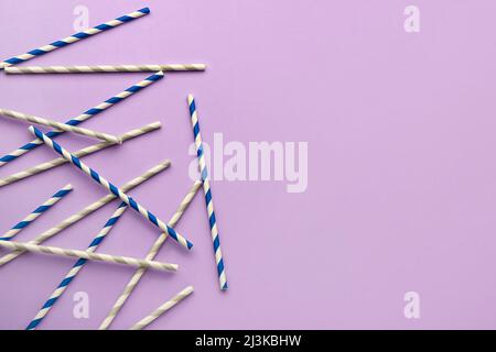 Stylish straws for drinks on purple background Stock Photo - Alamy