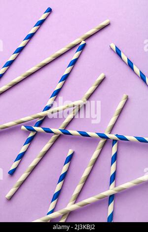 Stylish straws for drinks on purple background Stock Photo - Alamy