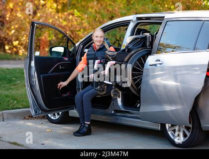 Young paraplegic woman moves from her wheelchair to the driver's seat ...