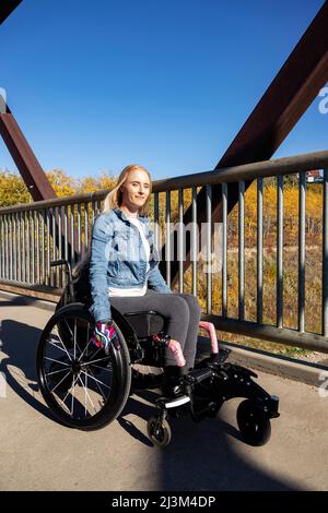 Young paraplegic woman going across a bridge using her wheelchair on a ...