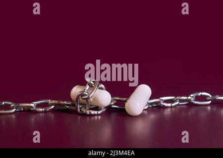 Drug addiction. White capsules, rewound by a chain Stock Photo - Alamy