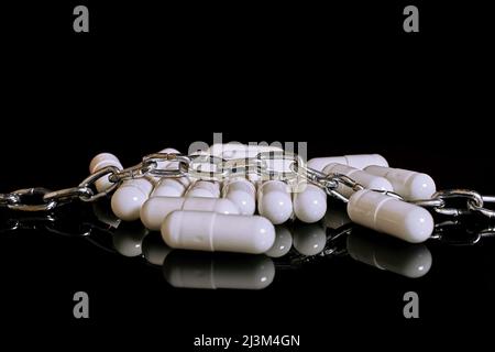 Drug addiction. White capsules, rewound by a chain Stock Photo - Alamy