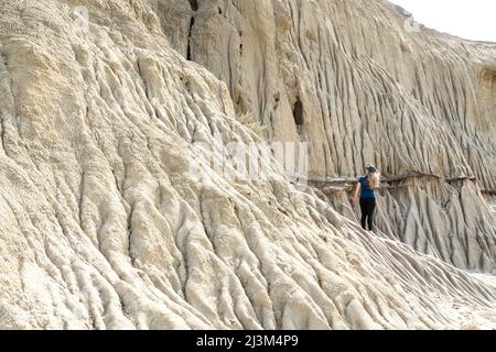 Woman standing on the eroded slopes in Big Muddy Badlands, viewing the ...