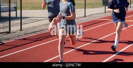 Three high school girls sprinting down an indoor track during an indoor ...